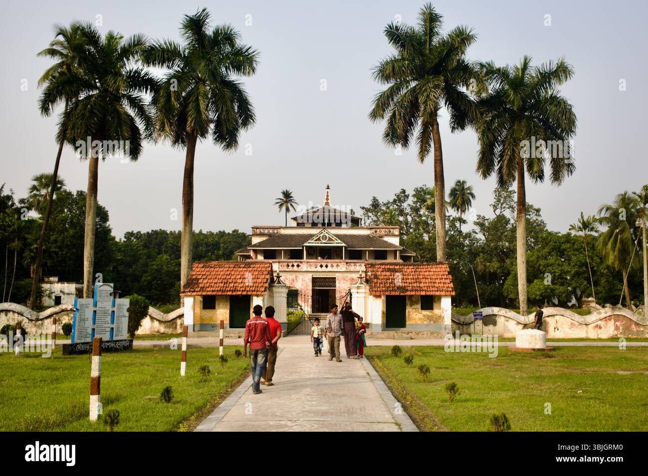 Visitors walk beneath towering palms toward the entrance of Shilaidaha ...