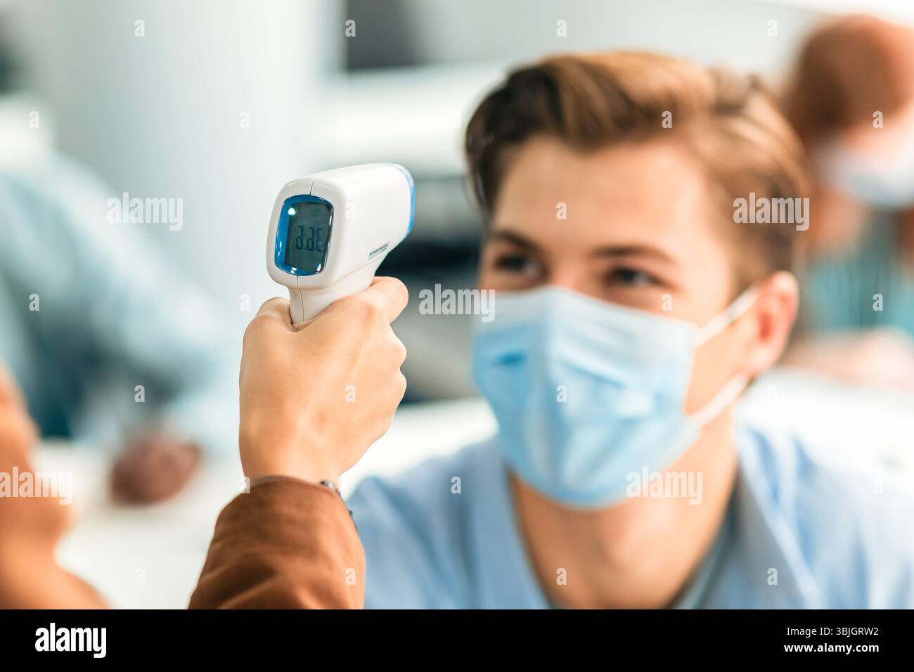 Teacher with contactless thermometer measuring temperature of student ...
