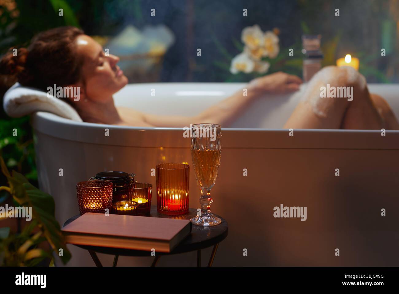 A woman with eyes closed finds tranquility in a steaming white bathtub ...