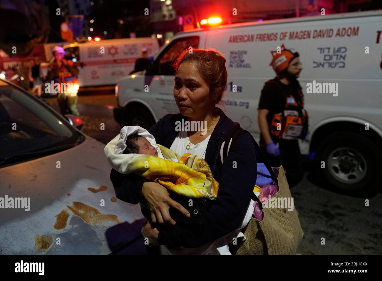 A woman hols a baby evacuates after a missile launched from Iran struck ...
