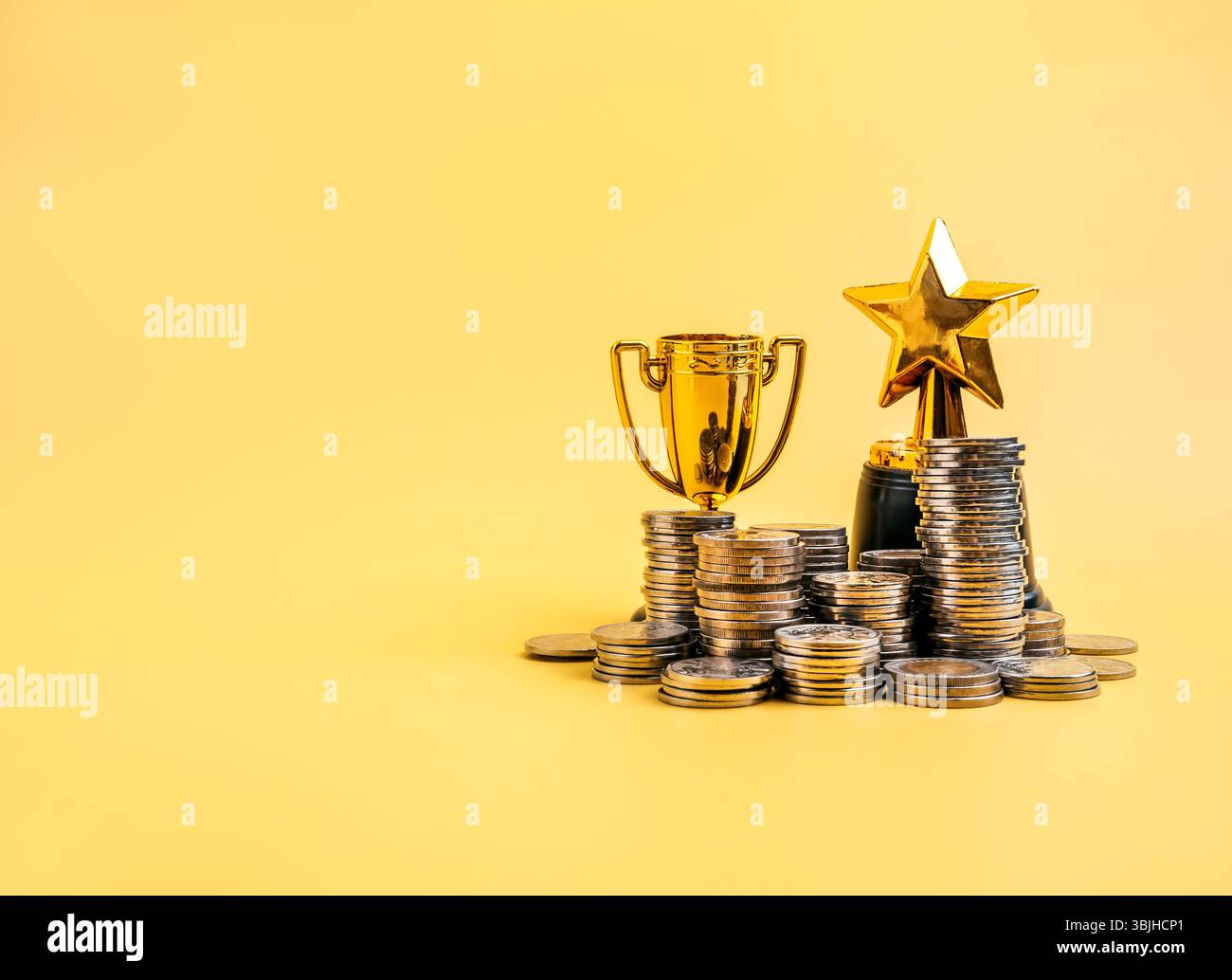 Many coin stacks with small gold cup and star trophy isolated on yellow ...