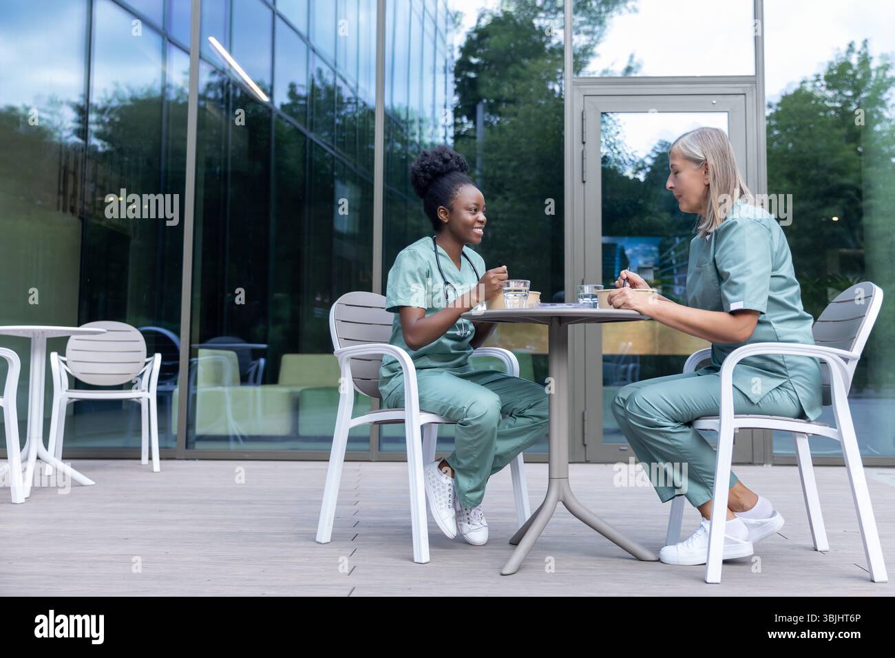 Two female doctors having lunch together and looking talking Stock ...
