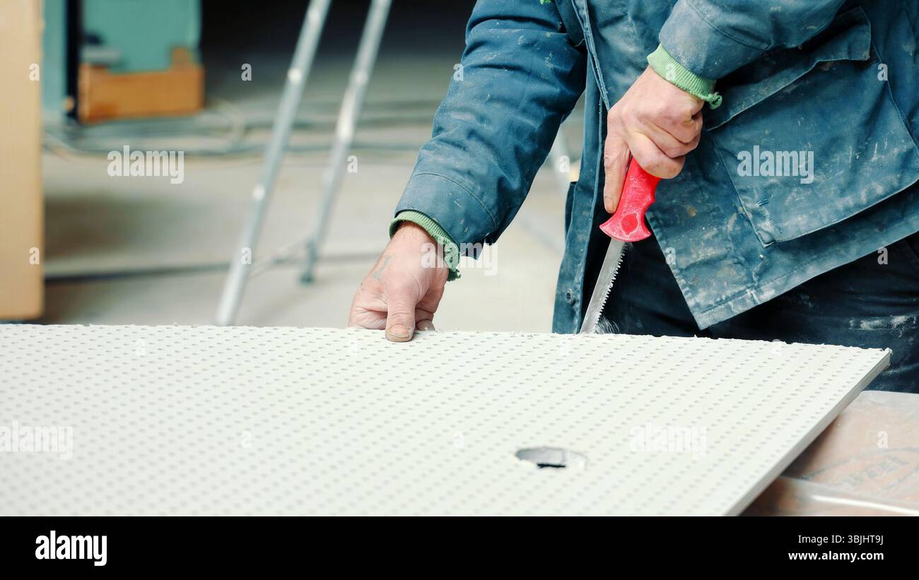 Construction Worker Cutting Insulation Board with Hand Saw. A ...