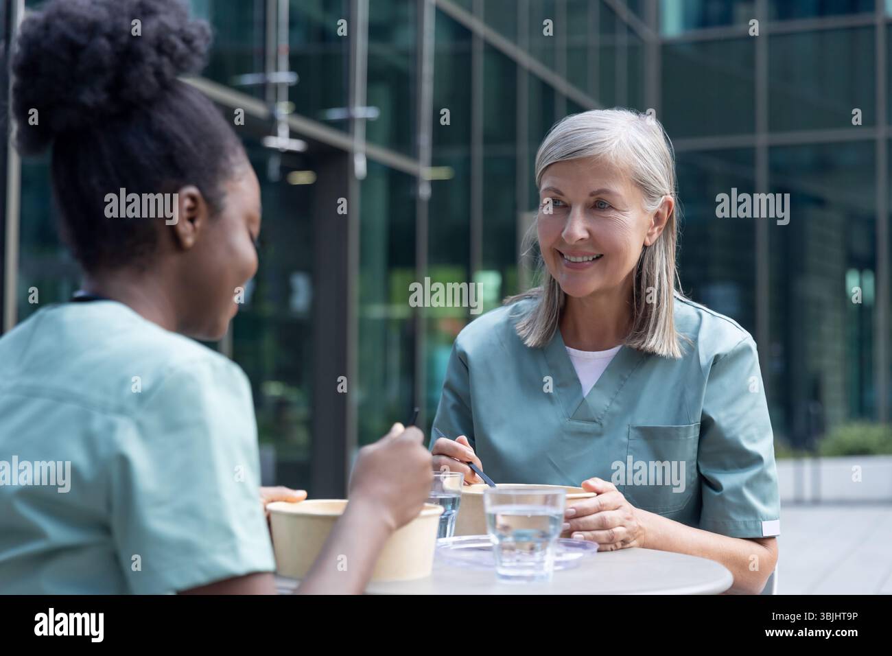 Female doctors having lunch together and looking involved while talking ...