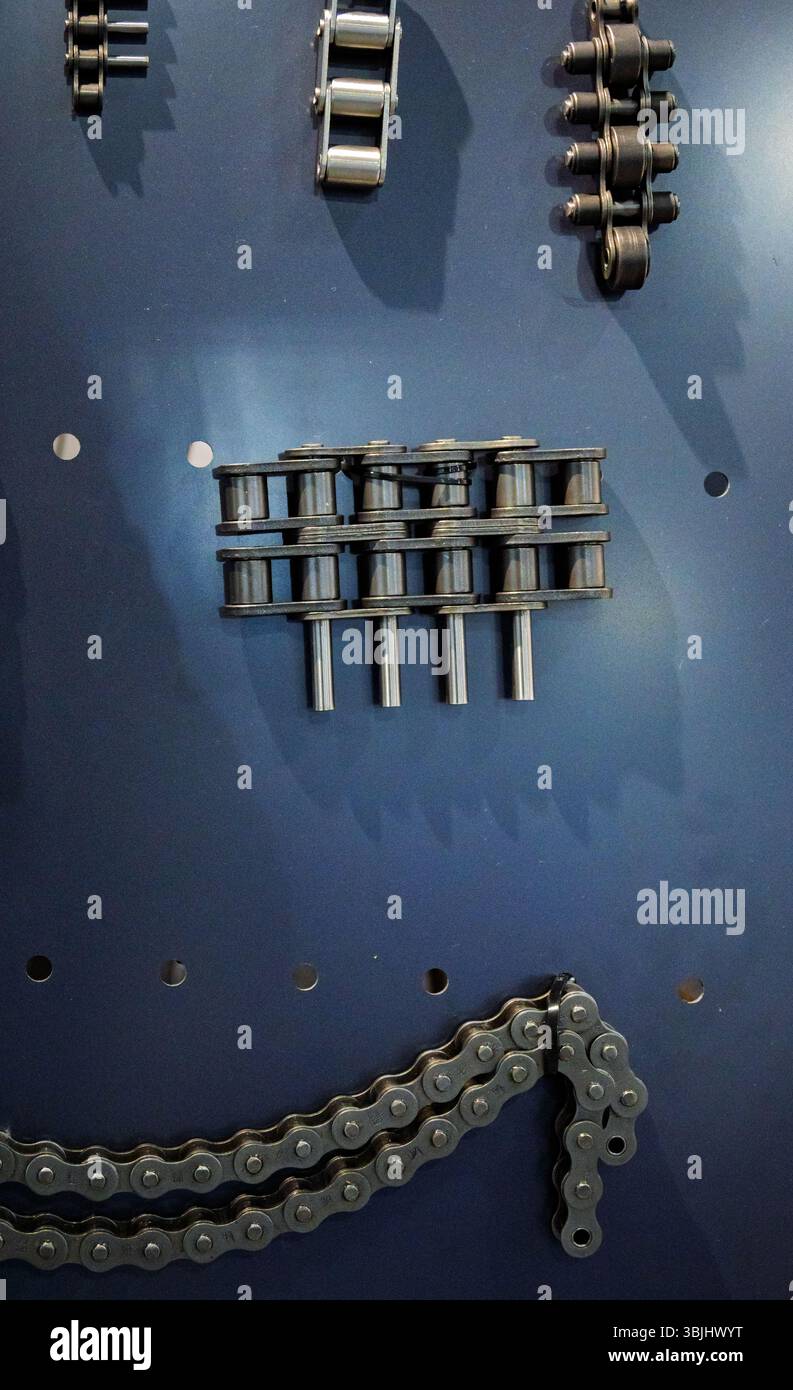 Close-up view of various industrial roller chains displayed on a dark ...