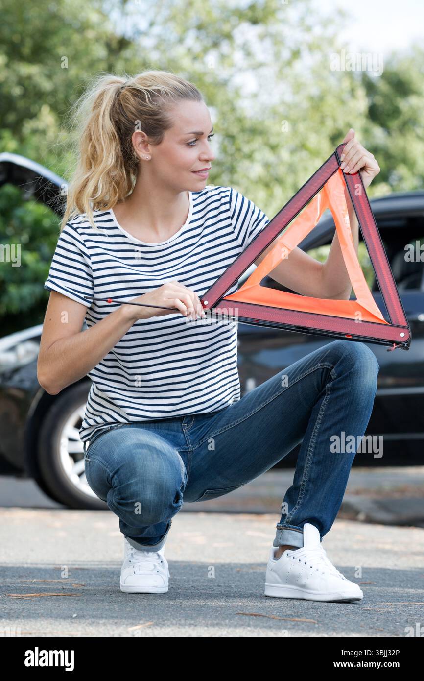 female motorist putting a safety triangle Stock Photo - Alamy