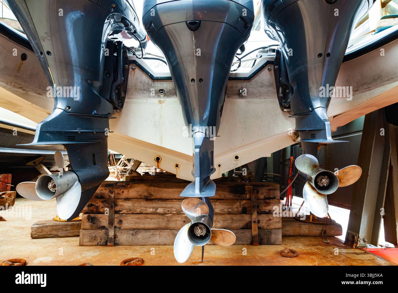 Three outboard motors mounted on a mount at the stern of a dry docked ...