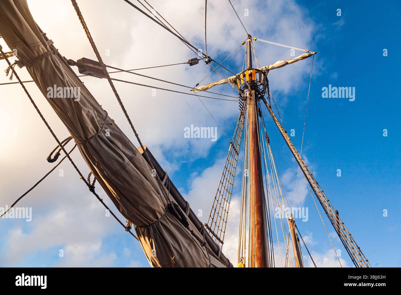 The mast of an old wooden ship with an observation basket on top, rope ...