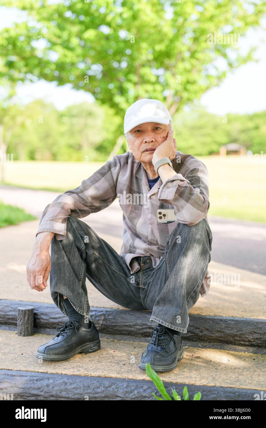 In a lush green park on a sunny May day, a Japanese man in his late 70s ...