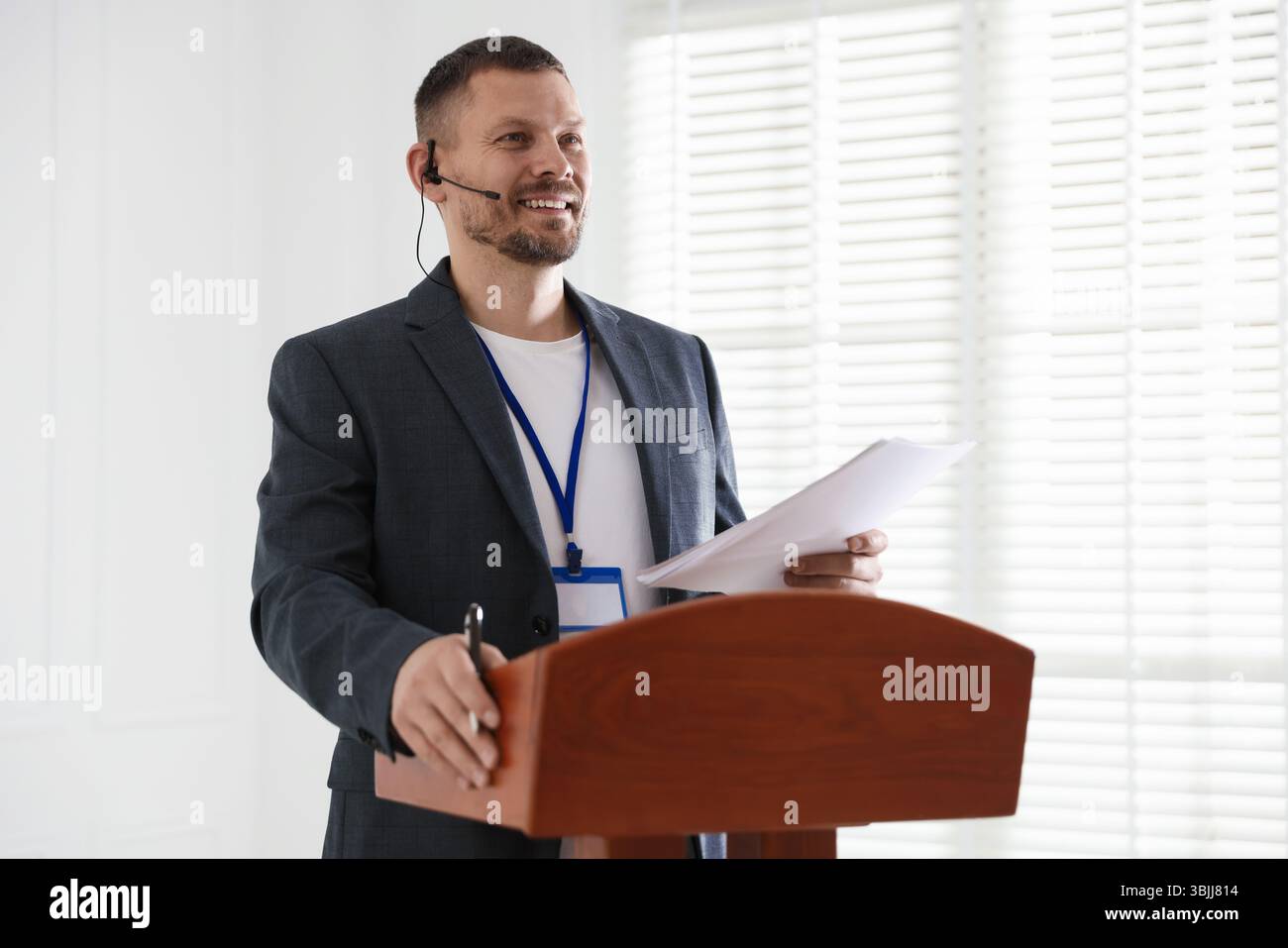 Man giving public speech with microphone at lectern indoors Stock Photo ...