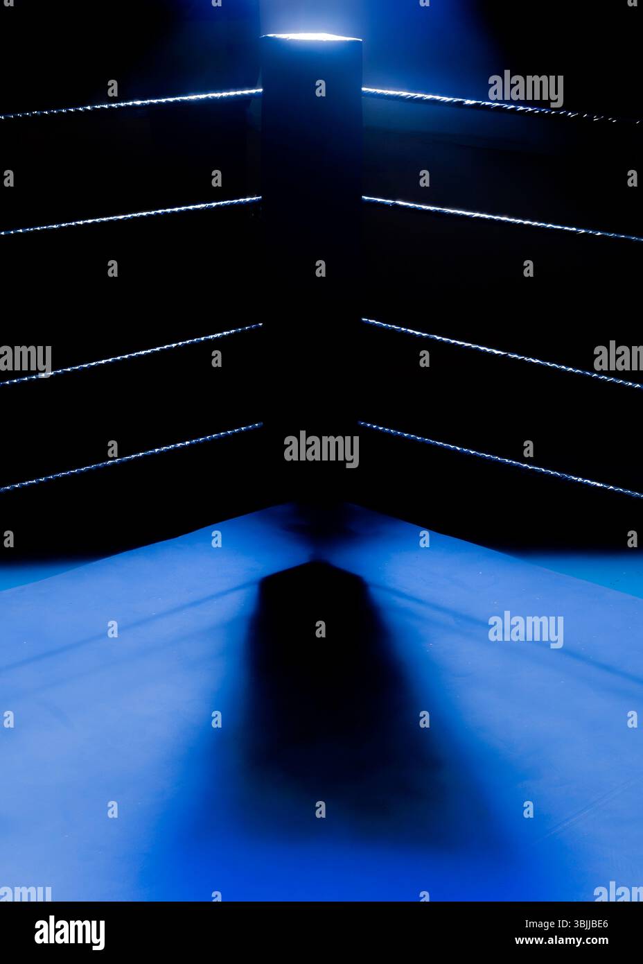 The corner of a boxing ring, illuminated by a spotlight from above. The ...