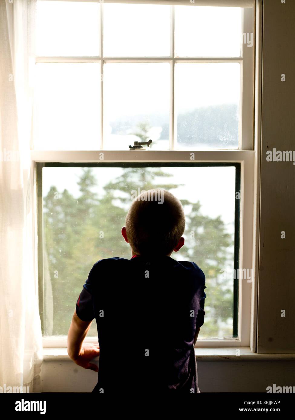 boy looks out window at maine ocean Stock Photo - Alamy