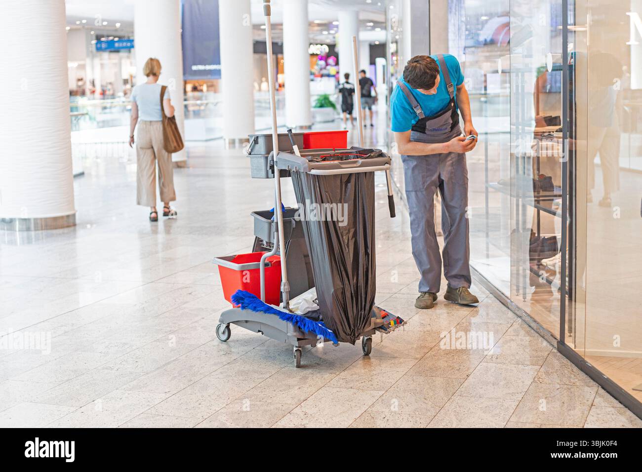 employee with cleaning machine wipes glass in the shop window of the ...