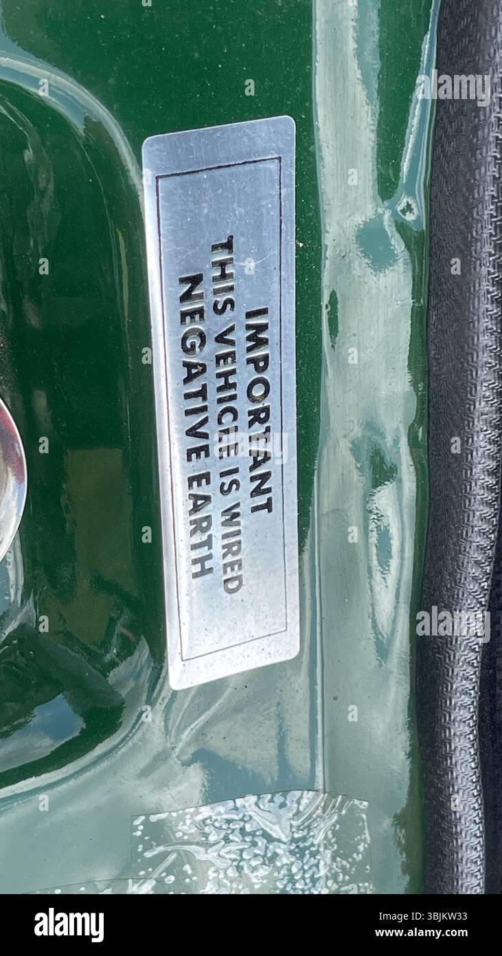 Metal label reading “Negative Earth” affixed to green-painted surface ...