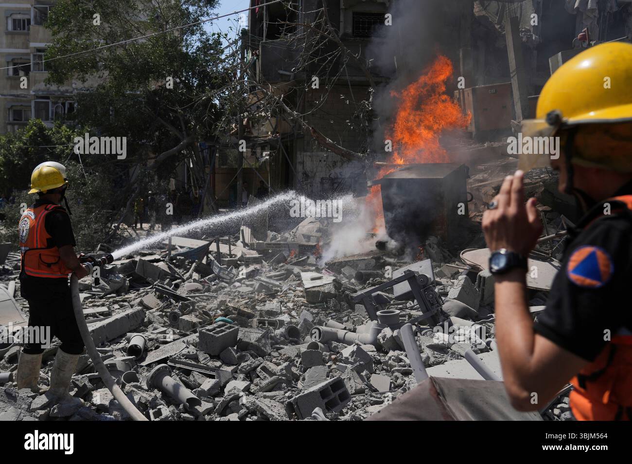 Palestinian firefighters work to extinguish a fire following an Israeli ...