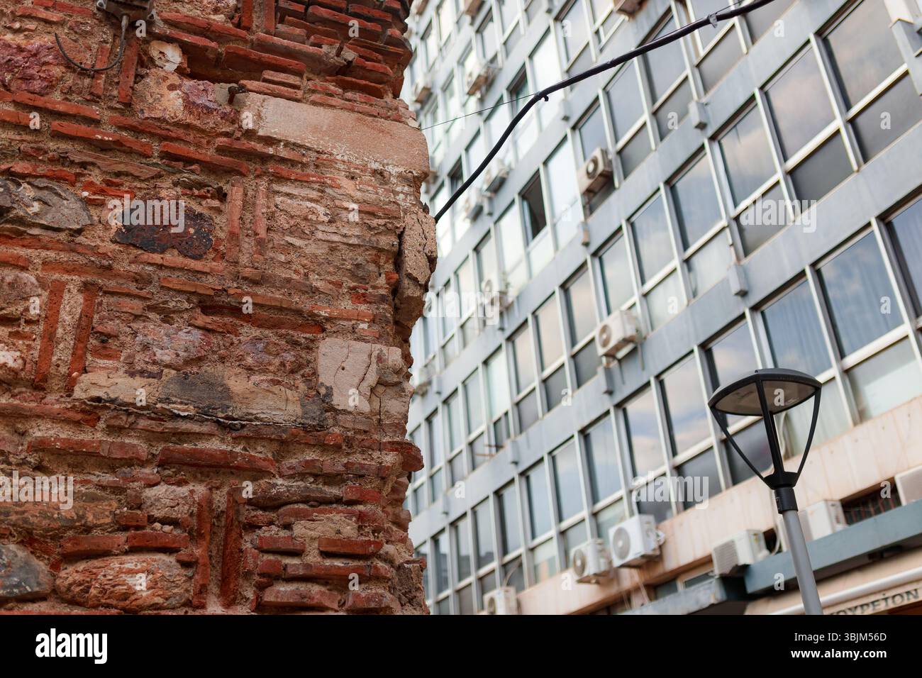 Weathered red-brick ruin wall beside modern glass office building Stock ...