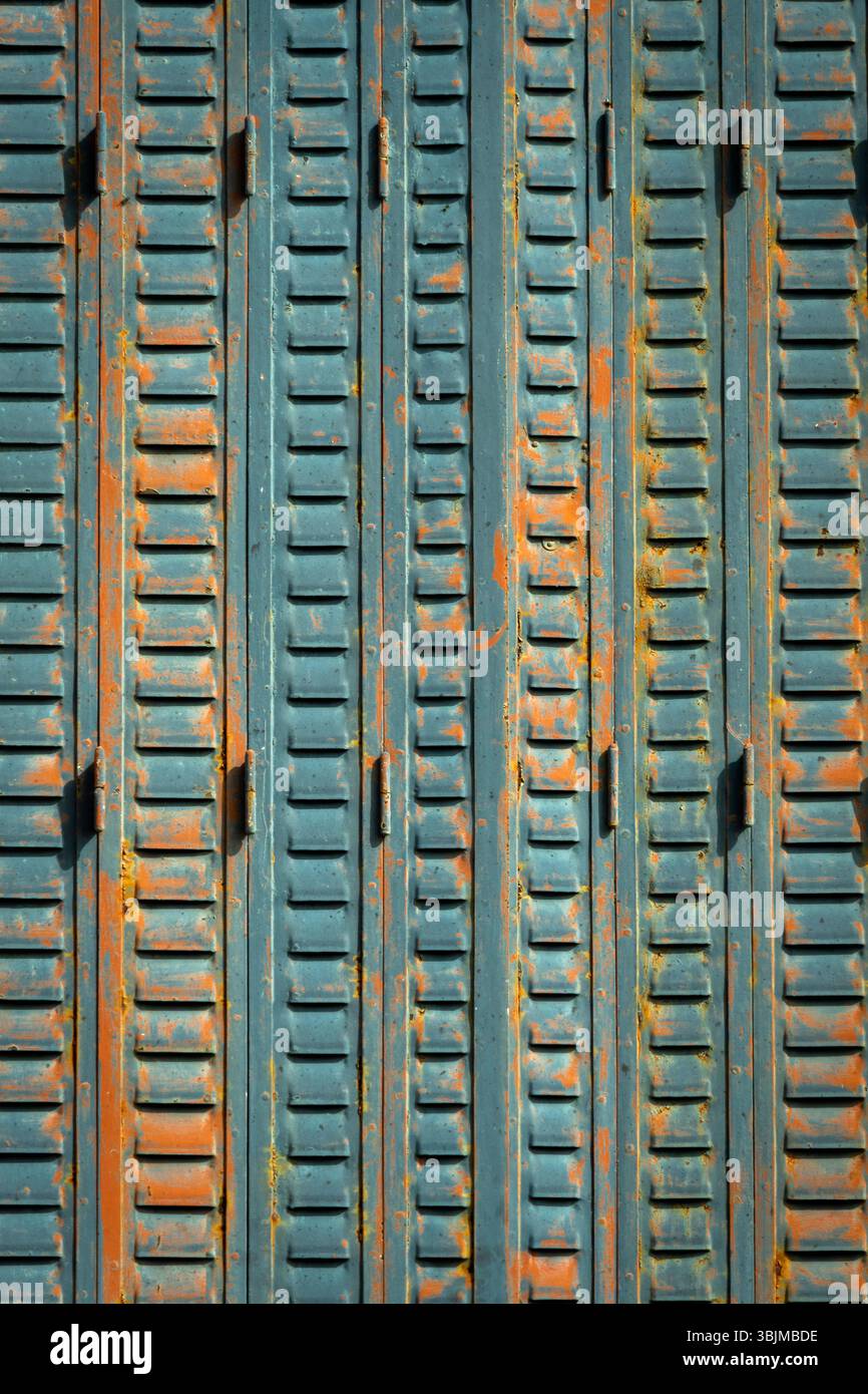 A close-up view of weathered metal shutters displaying a mix of blue ...