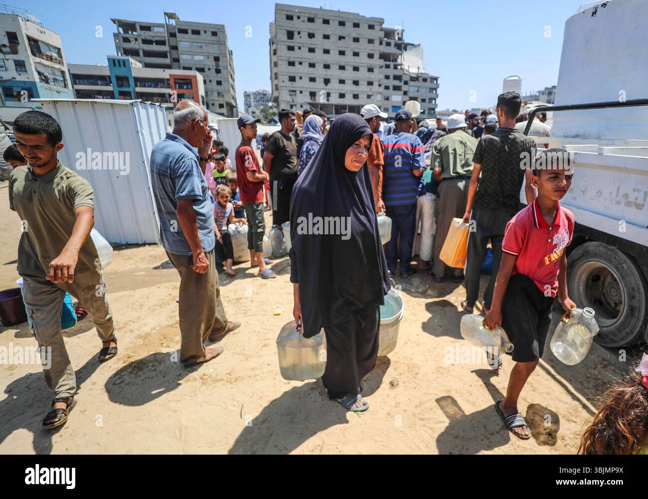 Palestinians carry jerry cans filled with water distributed by a water ...