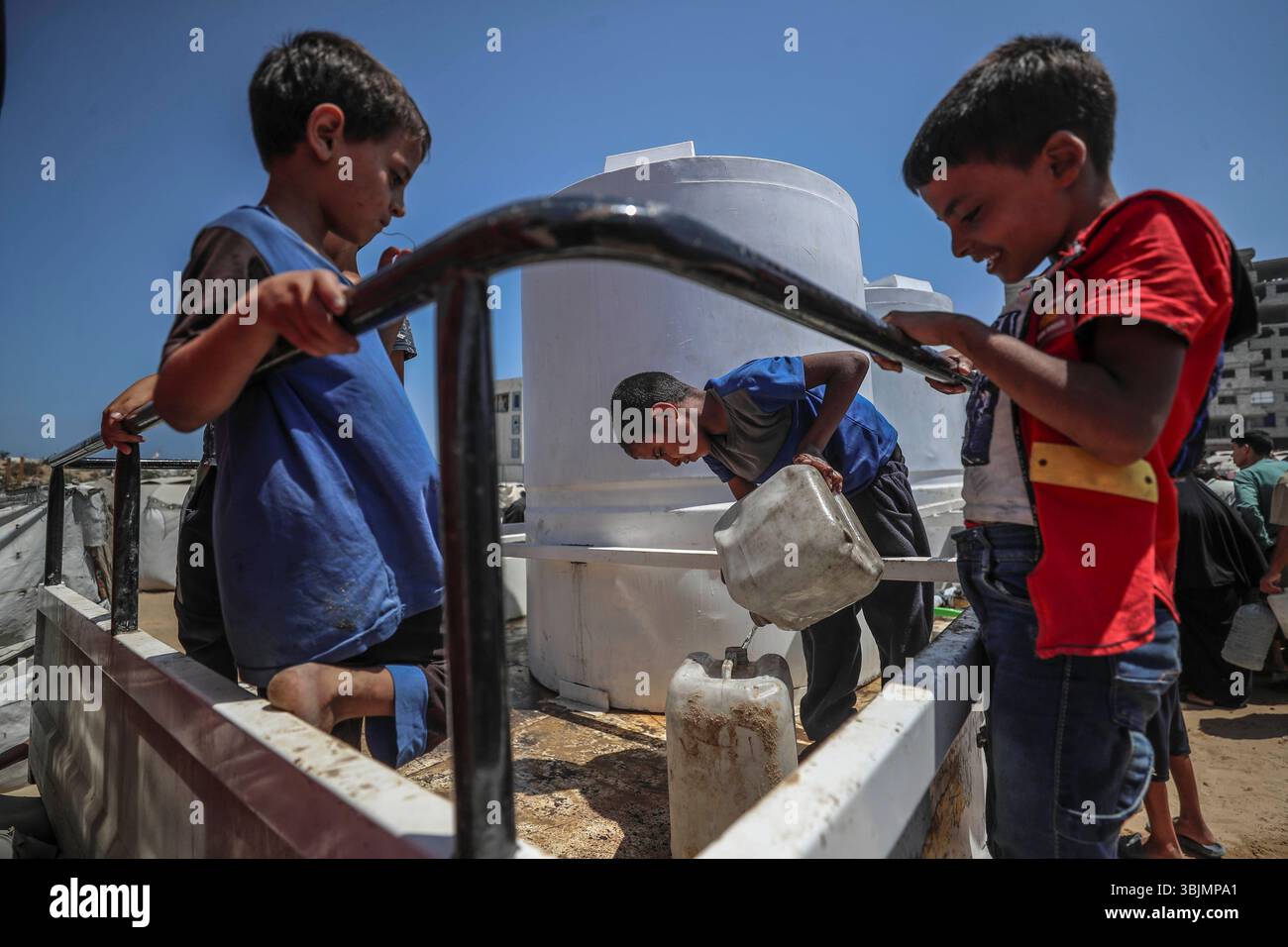 Palestinians carry jerry cans filled with water distributed by a water ...