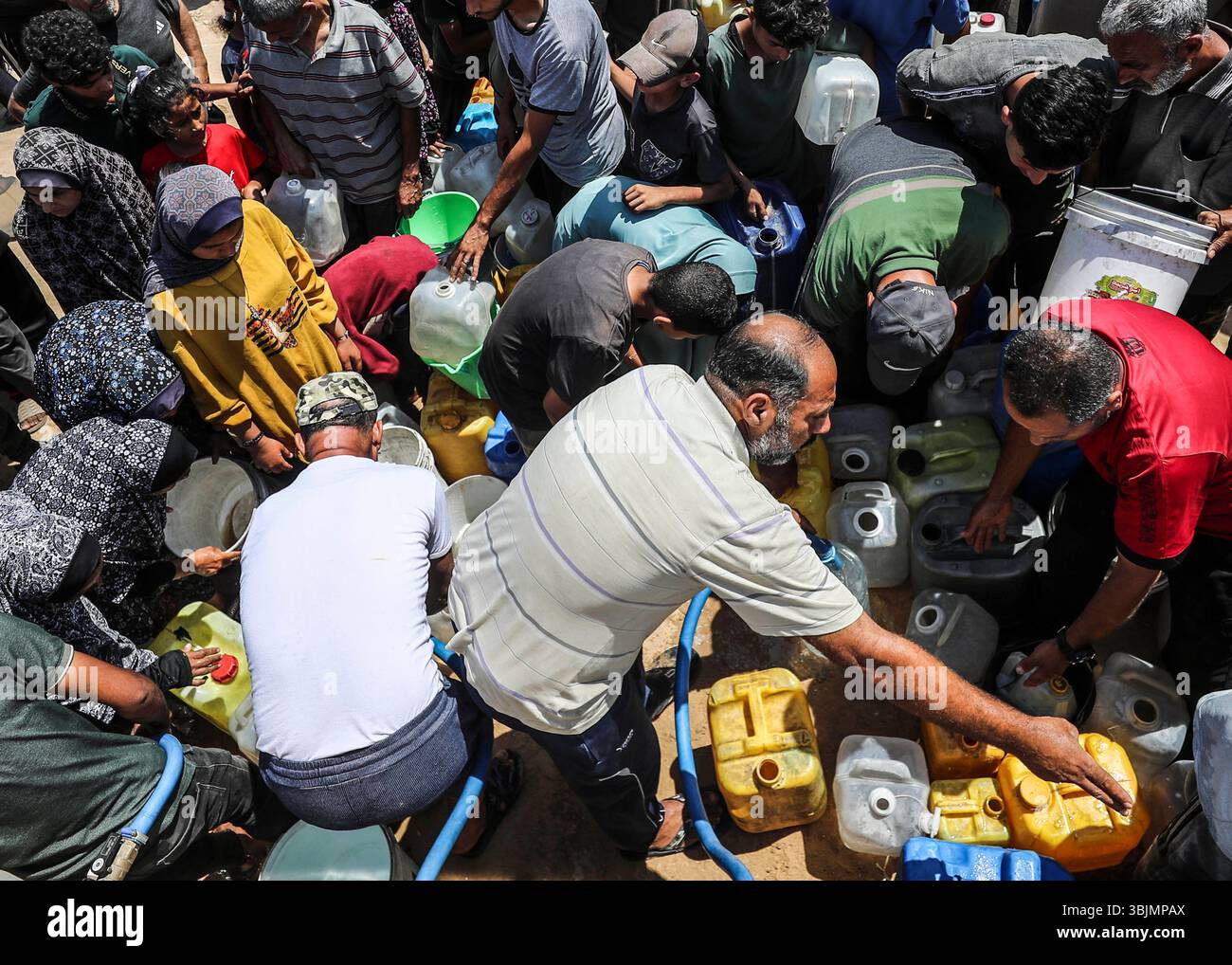 Palestinians carry jerry cans filled with water distributed by a water ...