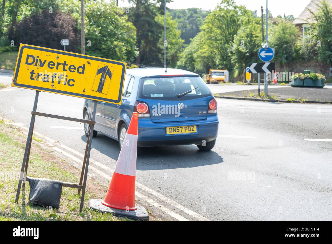 Yellow diverted traffic sign alongside a traffic cone on a mini ...
