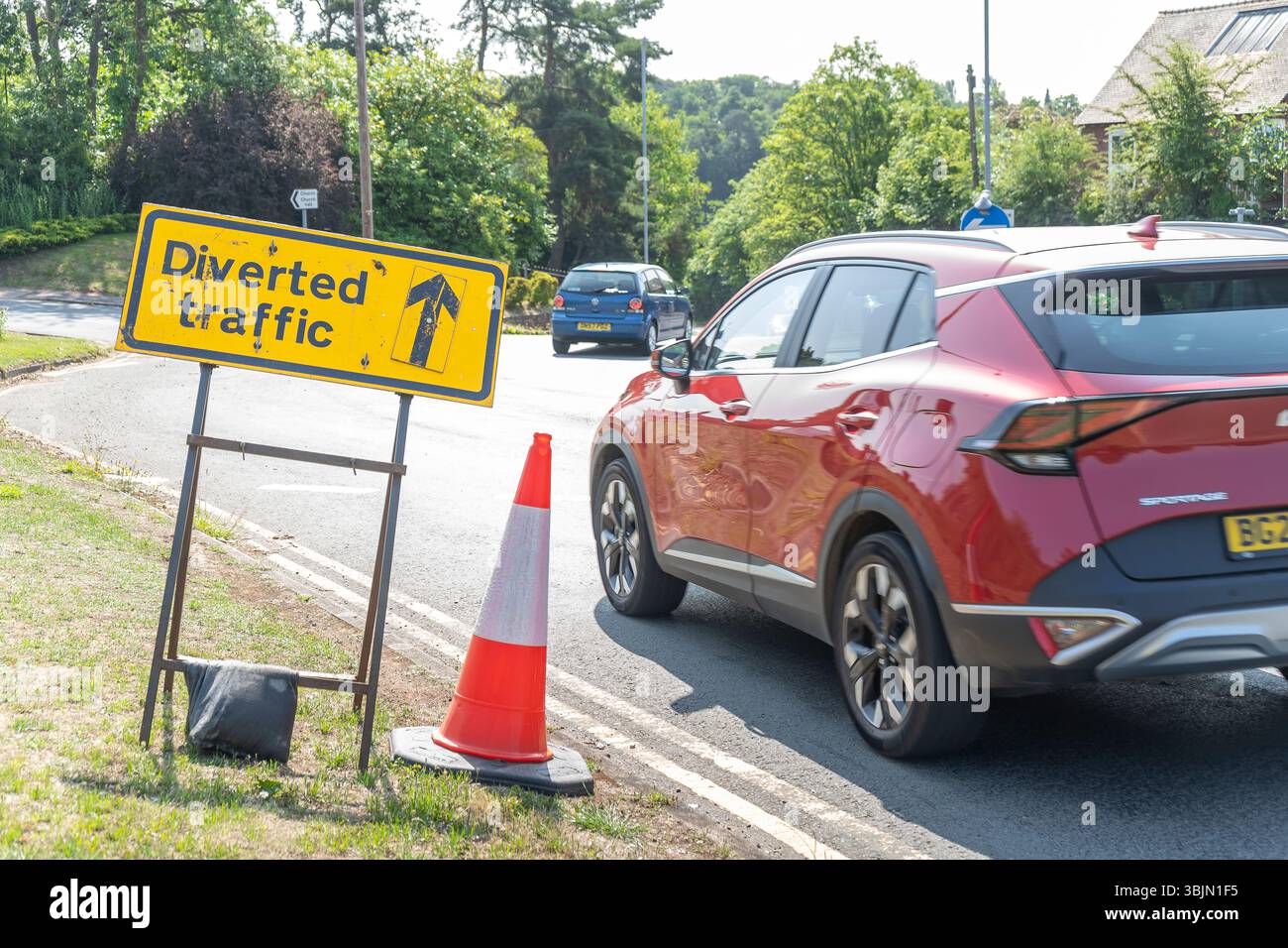 Yellow diverted traffic sign alongside a traffic cone on a mini ...
