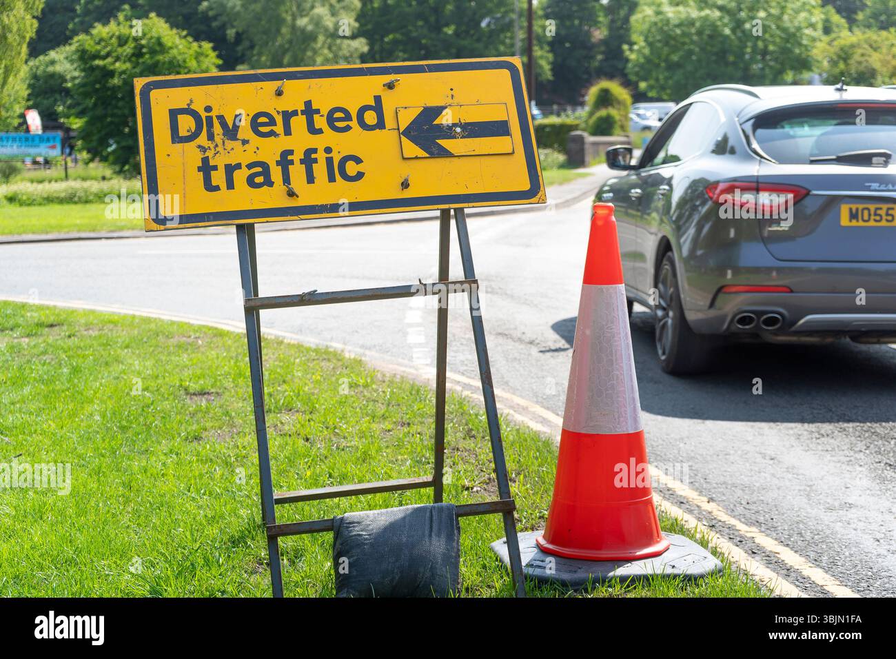 Yellow Diverted Traffic temporary road sign and traffic cone on grass ...