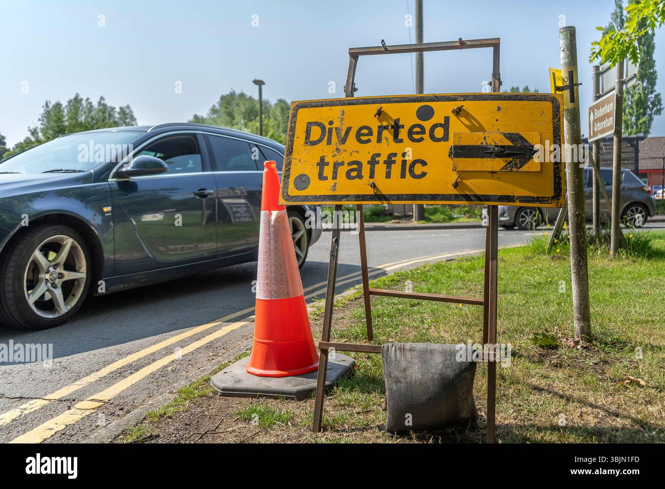 Yellow diverted traffic sign alongside a traffic cone on a mini ...