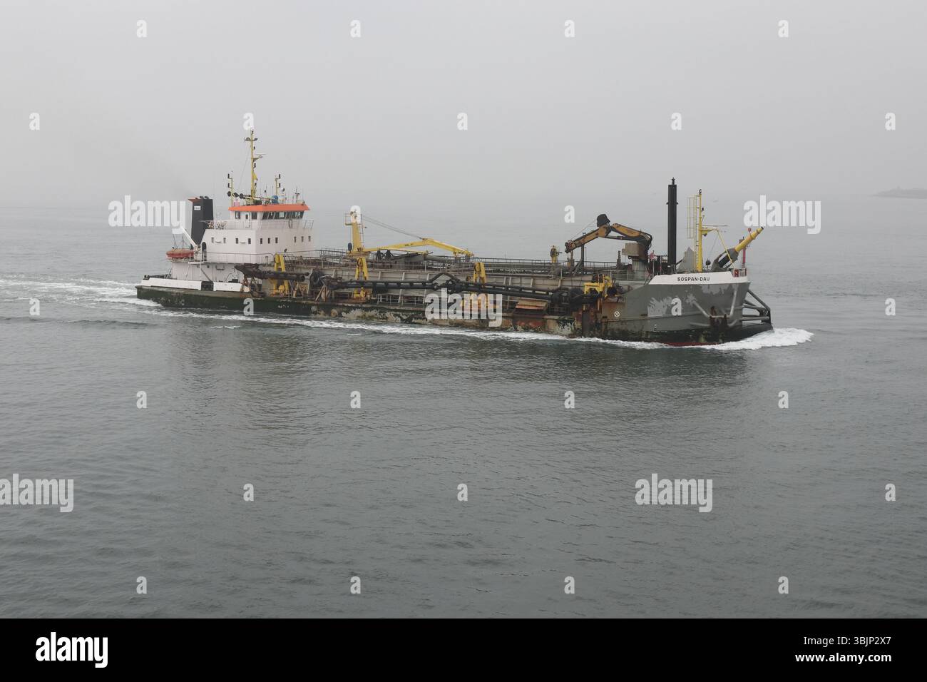 The trailing suction hopper dredger MV SOSPAN-DAU sails through a misty ...