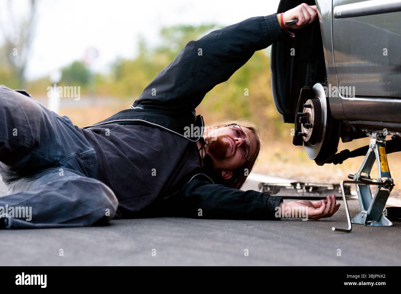 Handsome young man repairing flat tire hi-res stock photography and ...