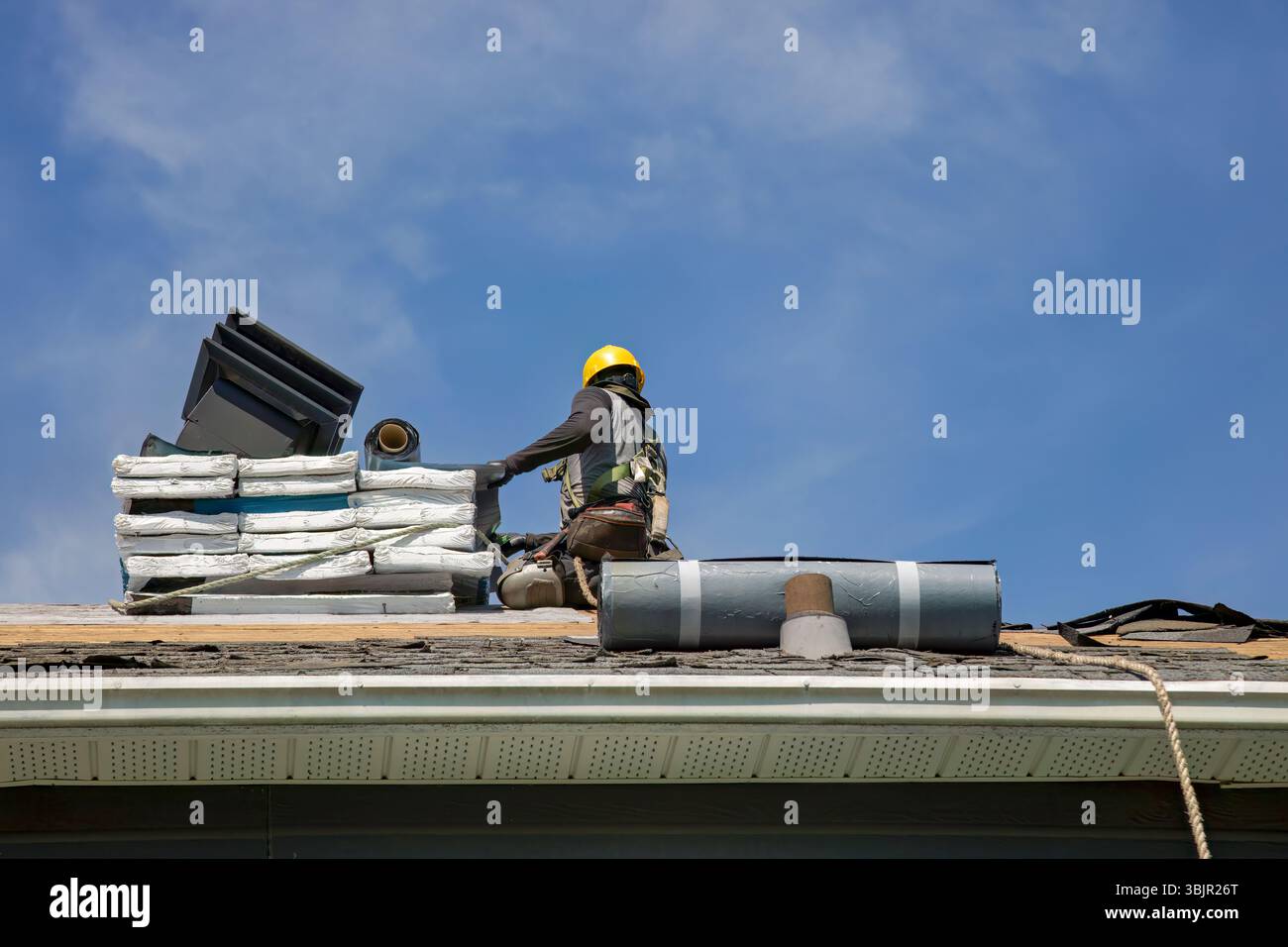 Construction worker wearing safety helmet applying roofing materials ...