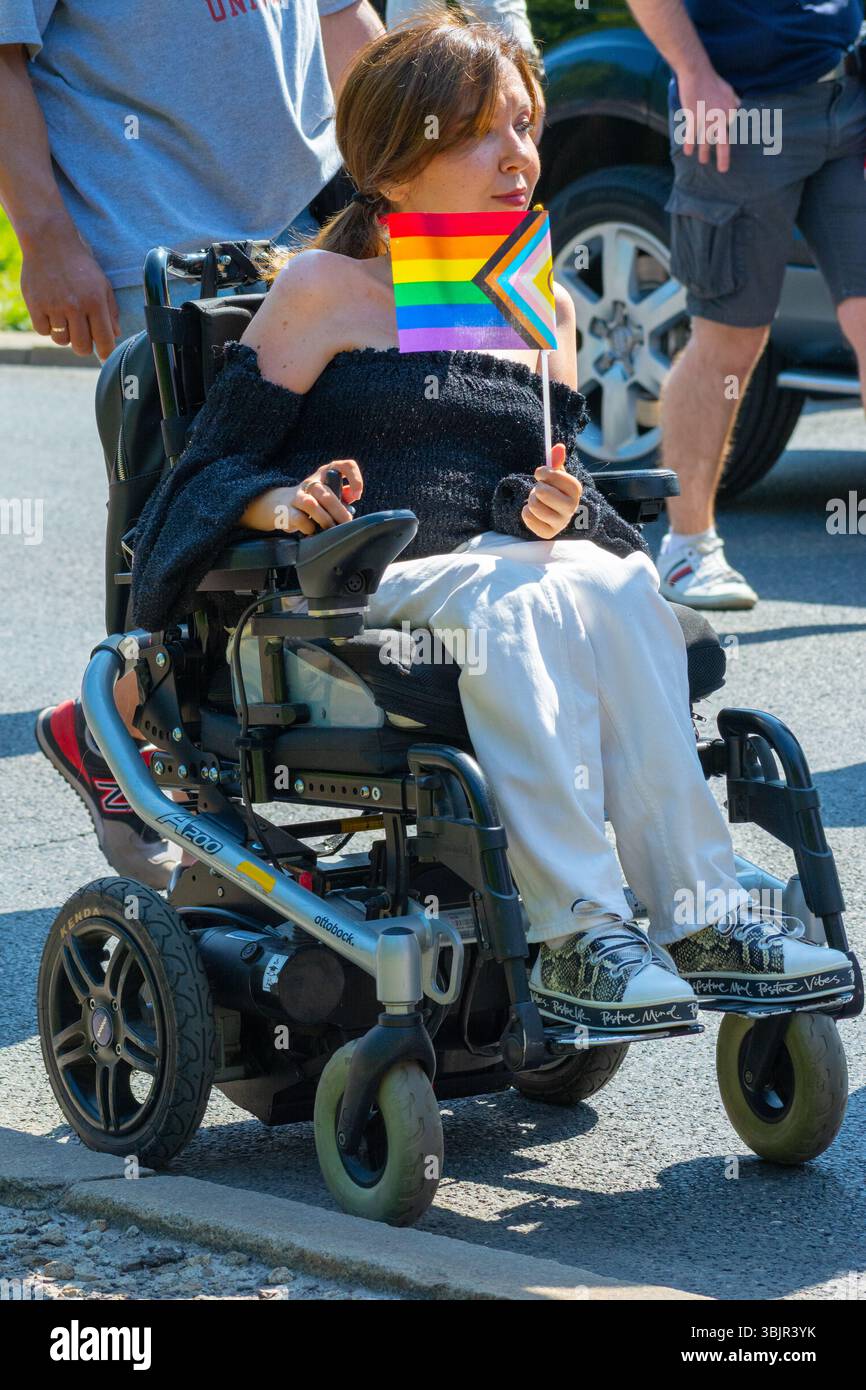 Participant in wheelchair holding rainbow pride flag at Parada Równości ...