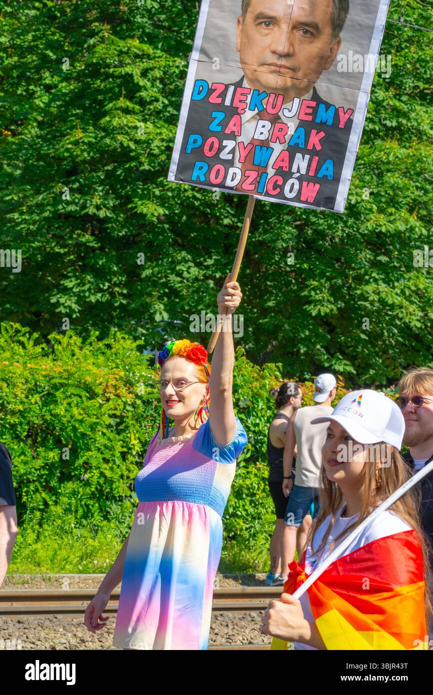 LGBTQ+ activists march with rainbow flags and a satirical sign ...