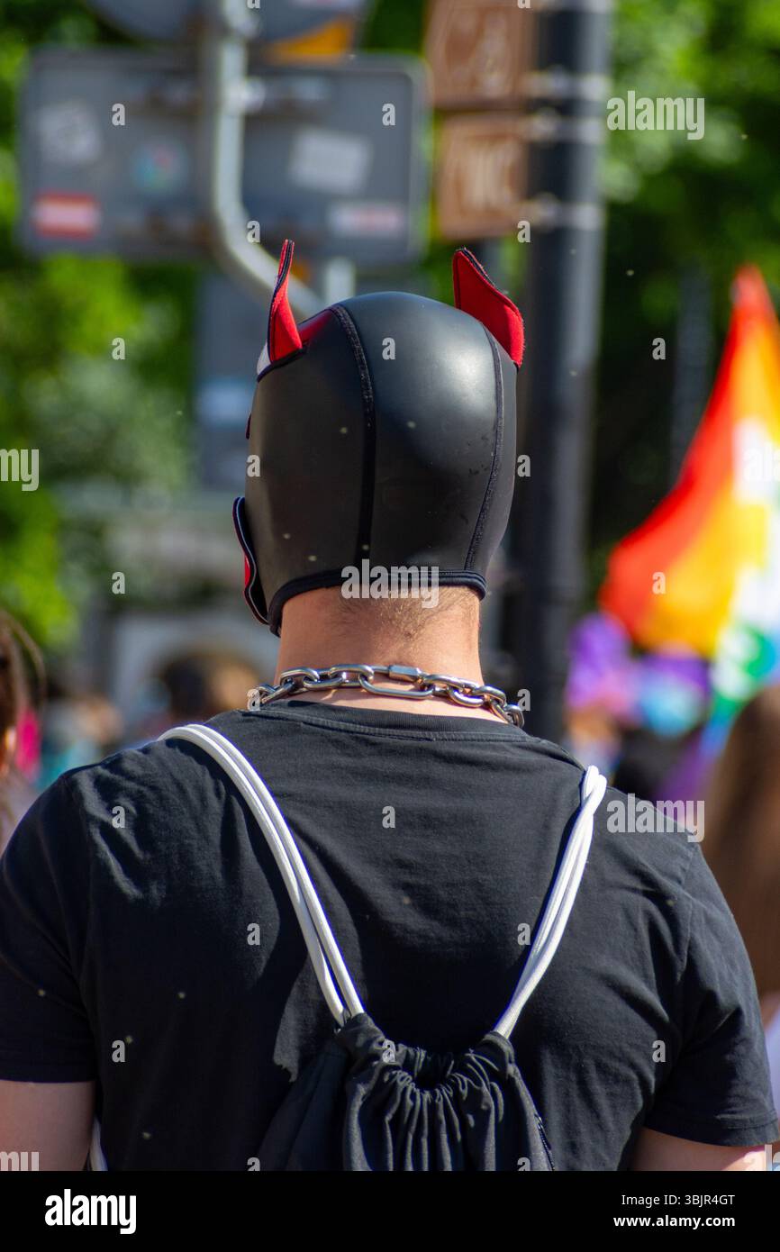 A parade participant wearing a devil horn helmet and chain necklace ...