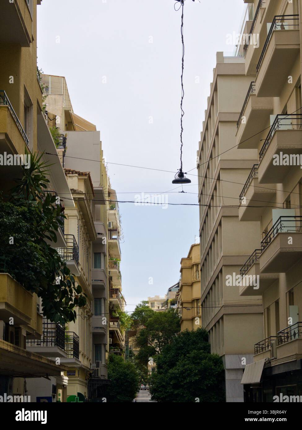 A tranquil uphill street in Athens, Greece, lined with yellow and white ...
