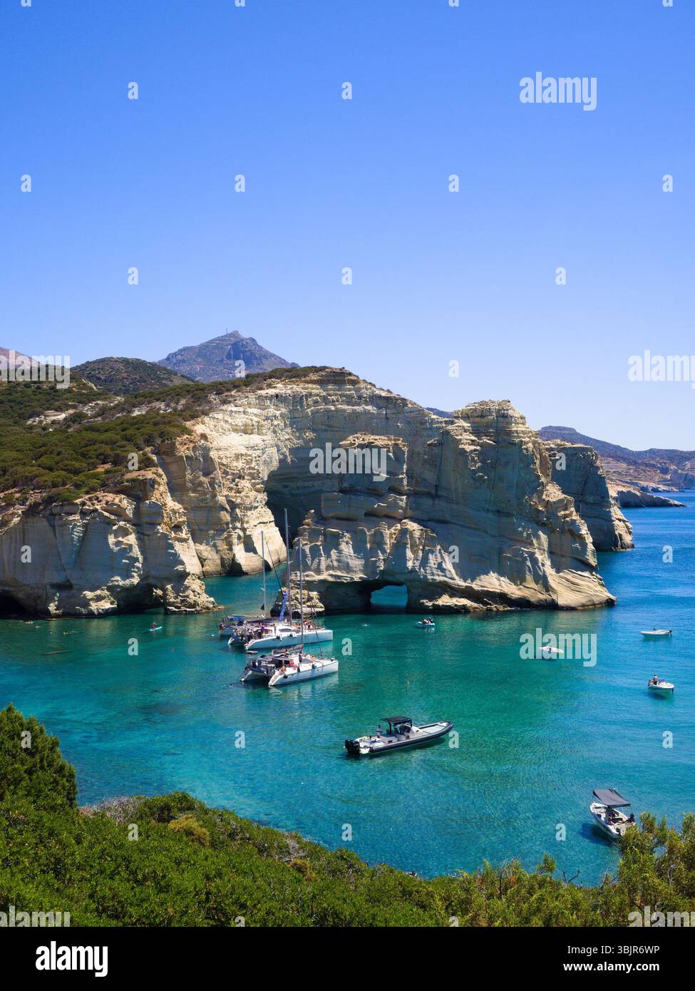 Limestone cliff at Kleftiko, Milos, with clear blue sea, boats floating ...
