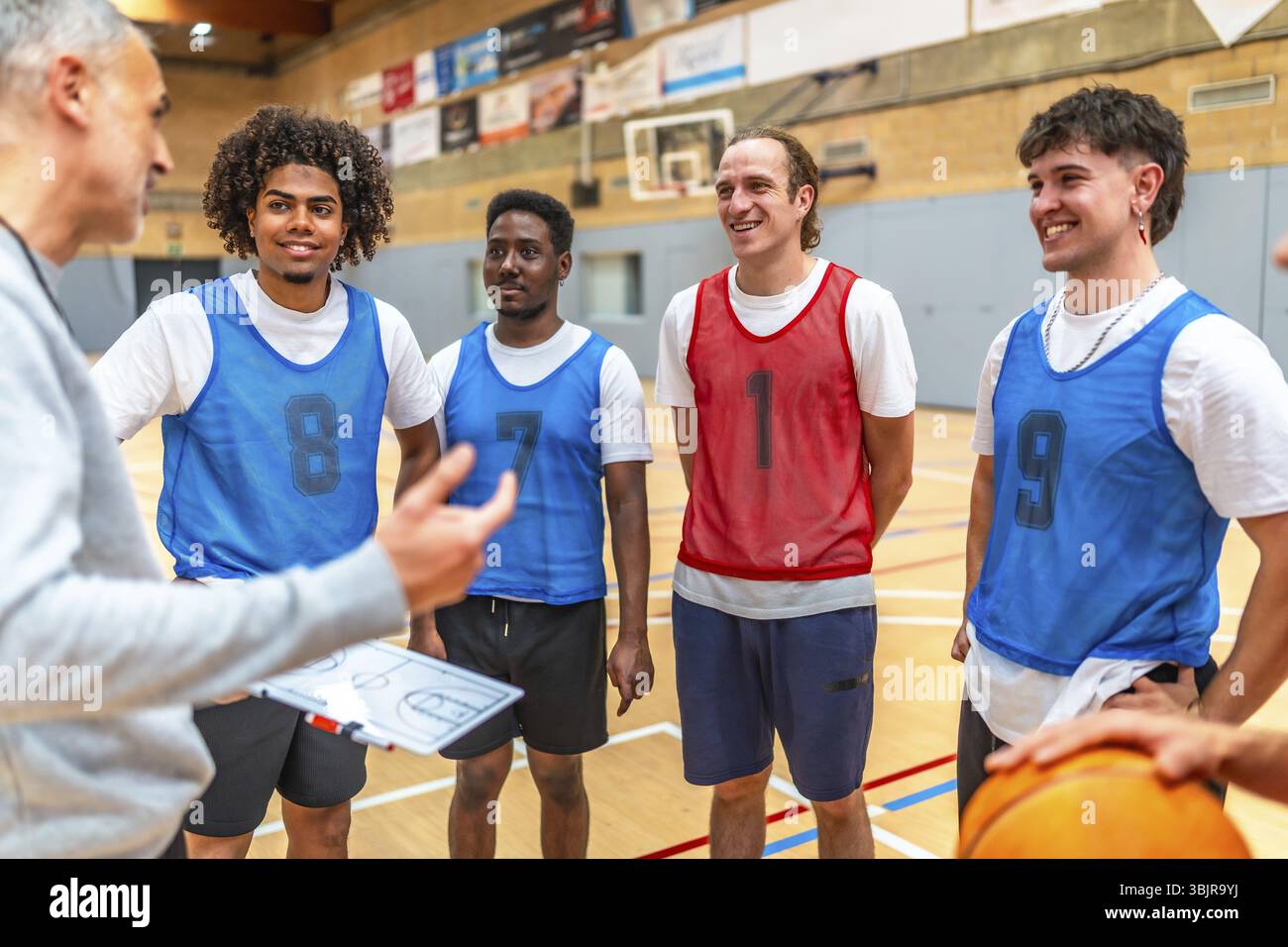 Coach holding clipboard explaining game strategy to his basketball team ...