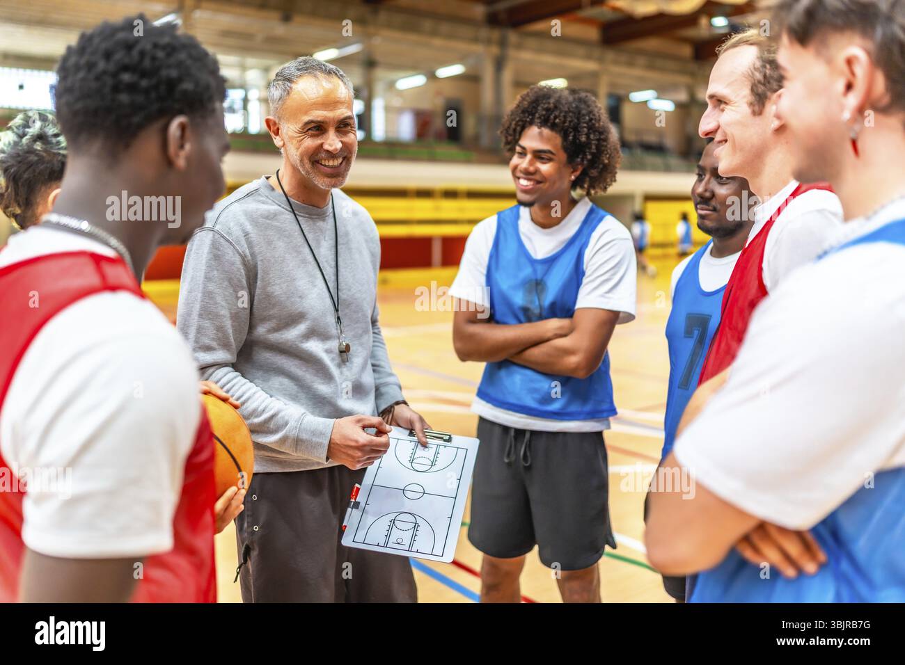 Basketball coach holding clipboard and explaining game strategy to his ...