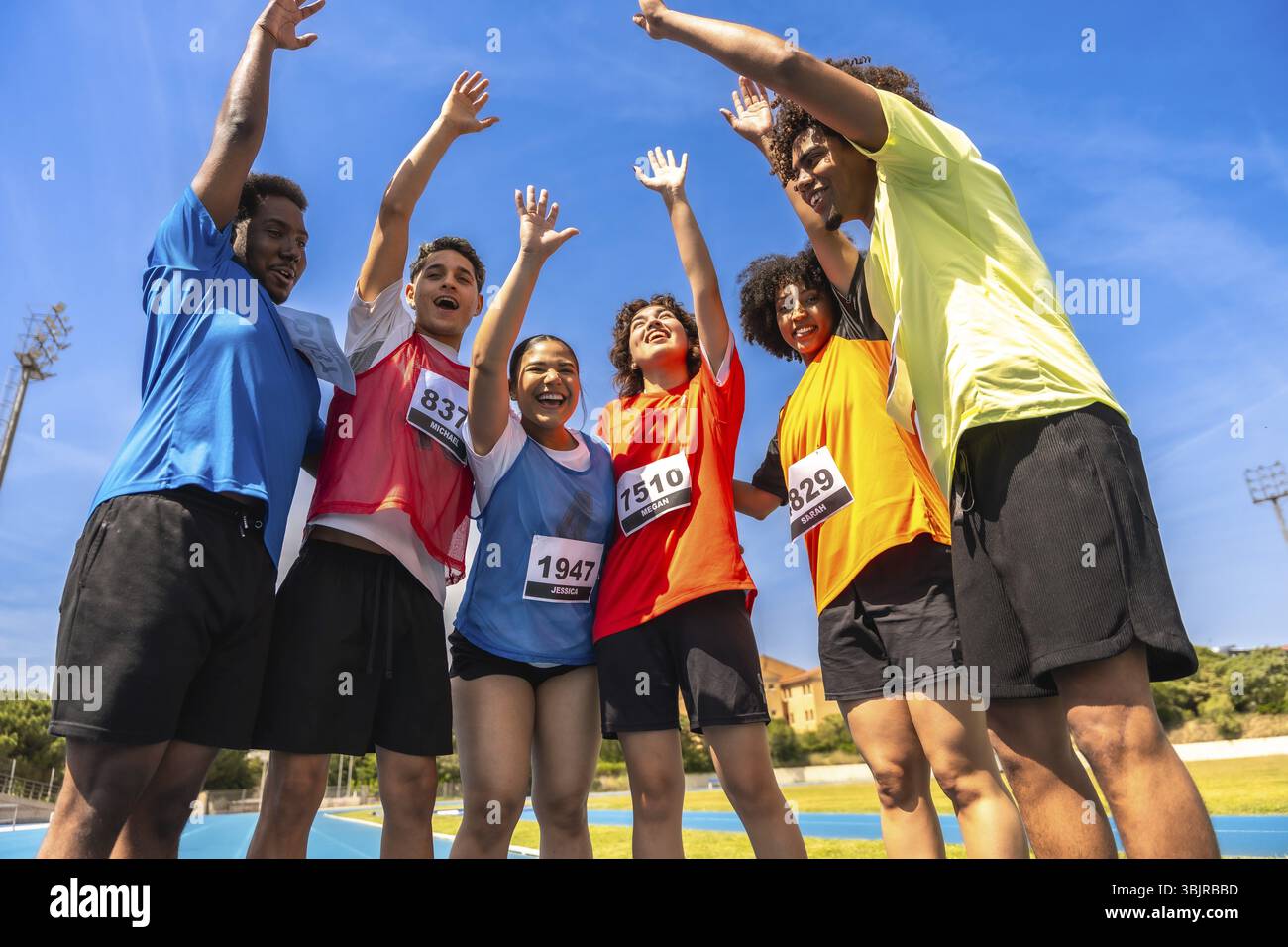 Group of young runners celebrating their victory with arms raised high ...