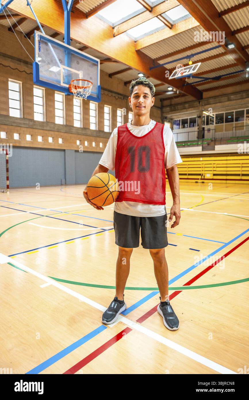 Young basketball player standing confidently on the court, holding a ...