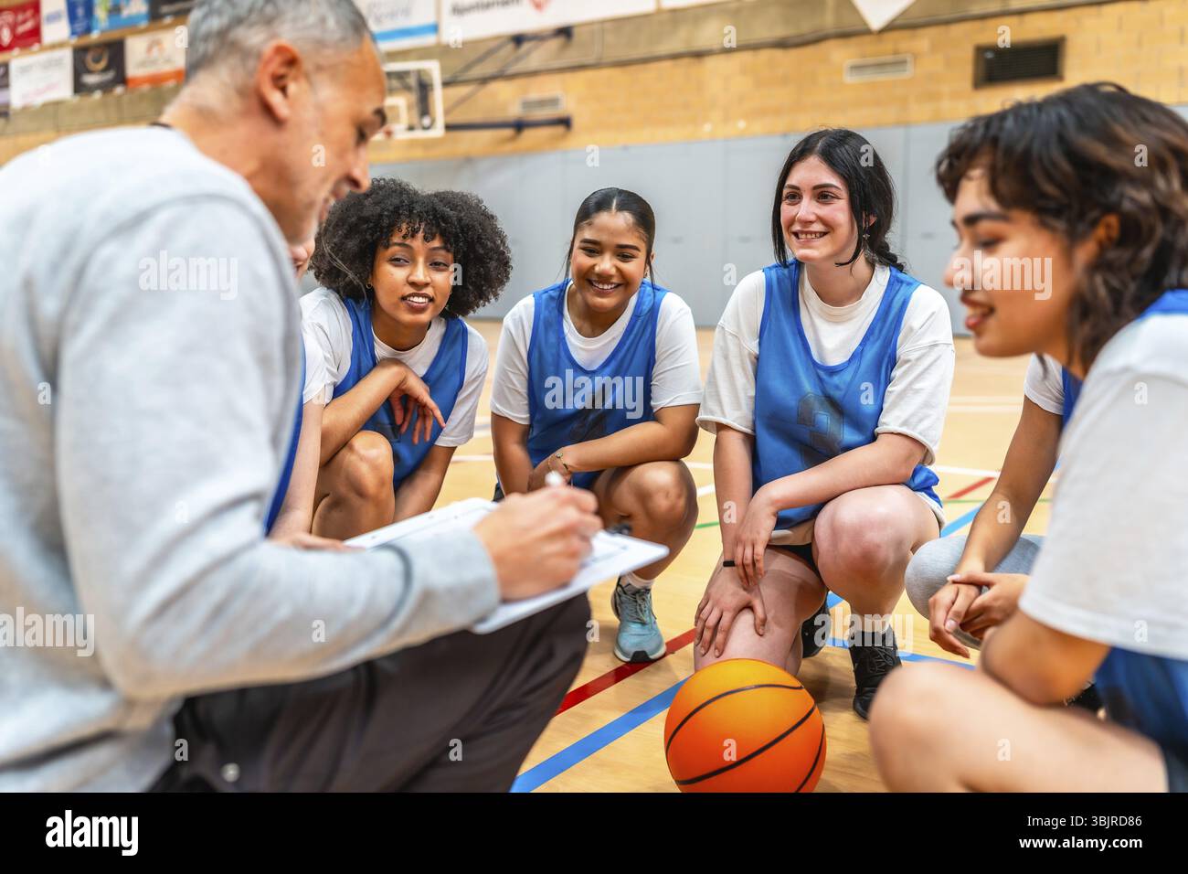 Basketball coach briefing his female team during a time out, taking ...