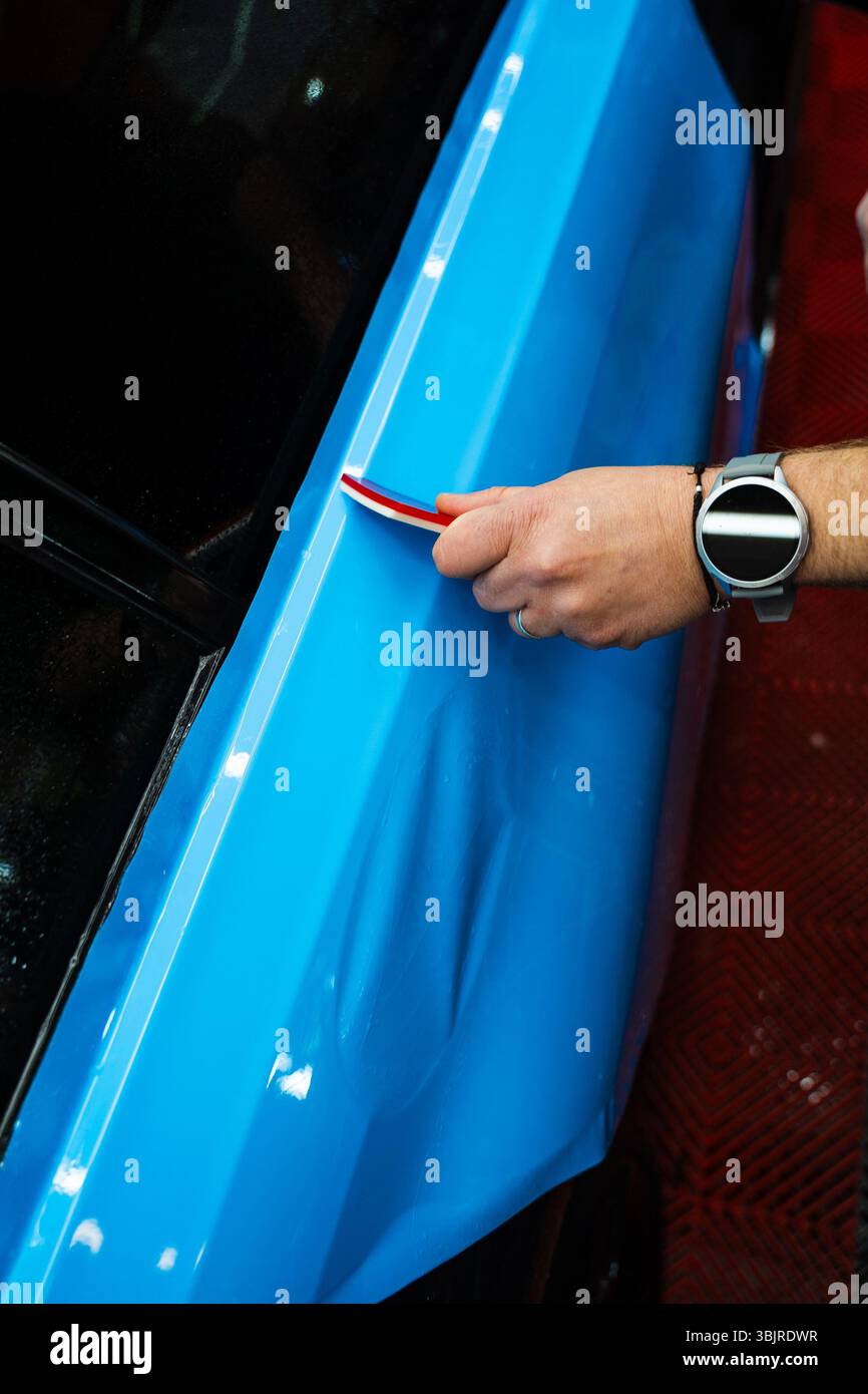 Vehicle wrap detailing involves squeegee strokes for seamless, wrinkle ...