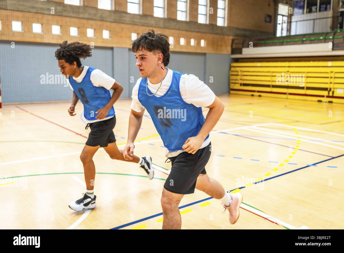 Two basketball players running on the court during training, practicing ...