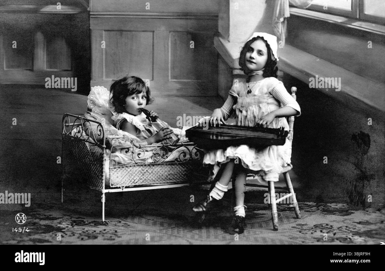 Two children making music, 1920s, Two girls, one in bed and one on a ...
