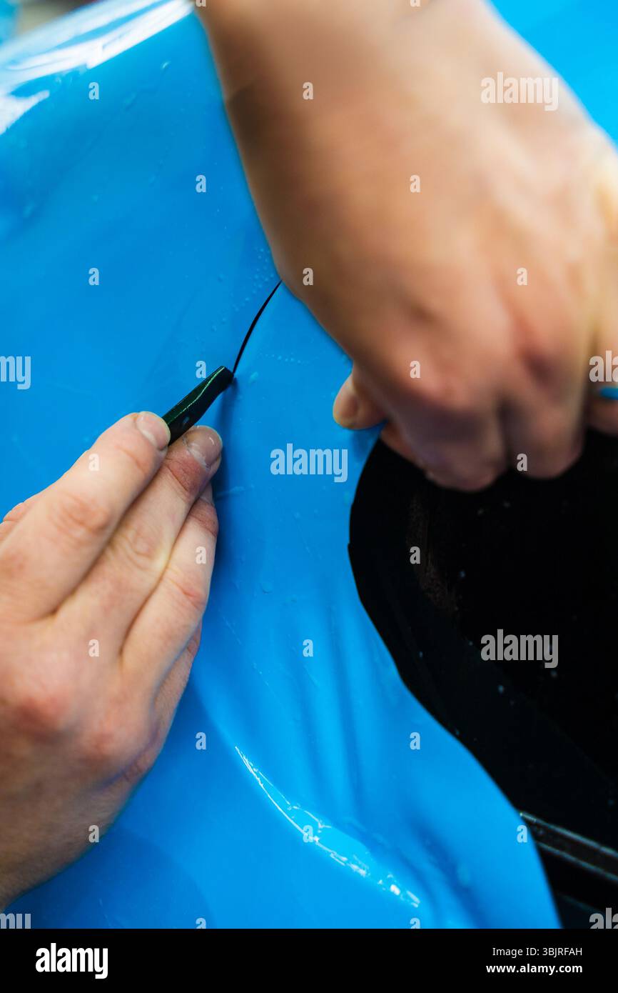 Cutting blue PPF with blade. Cutting blue paint protection film with ...