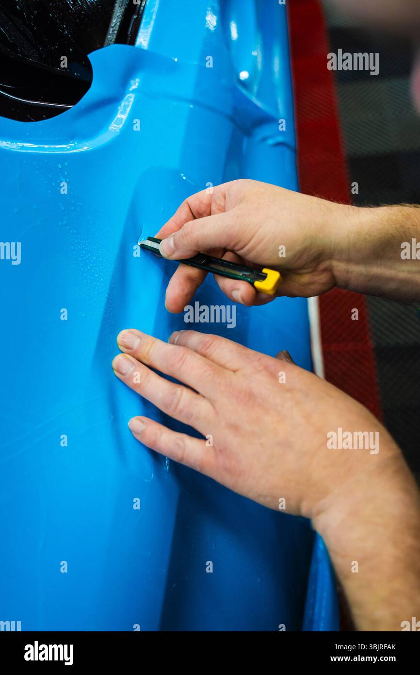 Cutting blue PPF with blade. Cutting blue paint protection film with ...