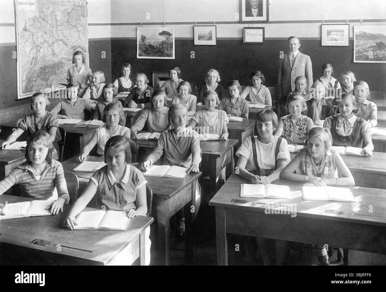 School class girls, 1930s, pupils and teacher in a classroom with maps ...