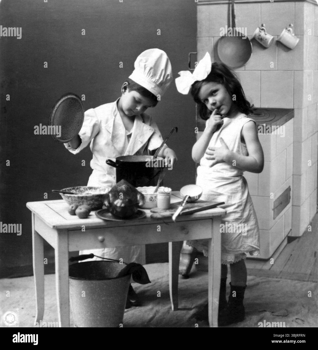 Two children cooking, 1920s, Two children playing in a kitchen, one in ...