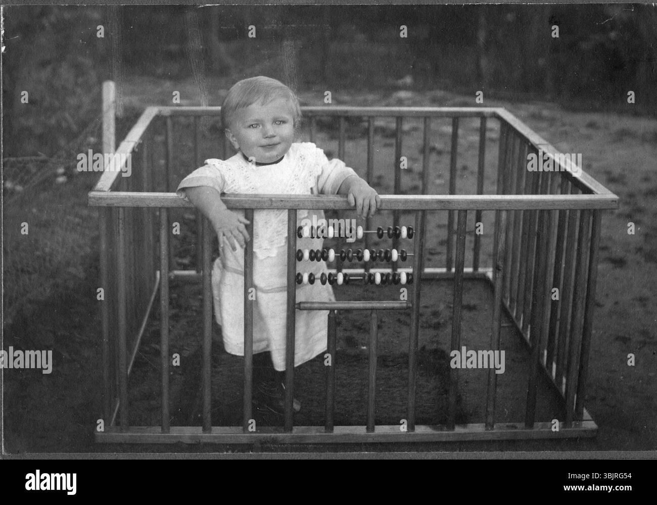 Child in a playpen, 1920s, A smiling child stands in a grid with an ...