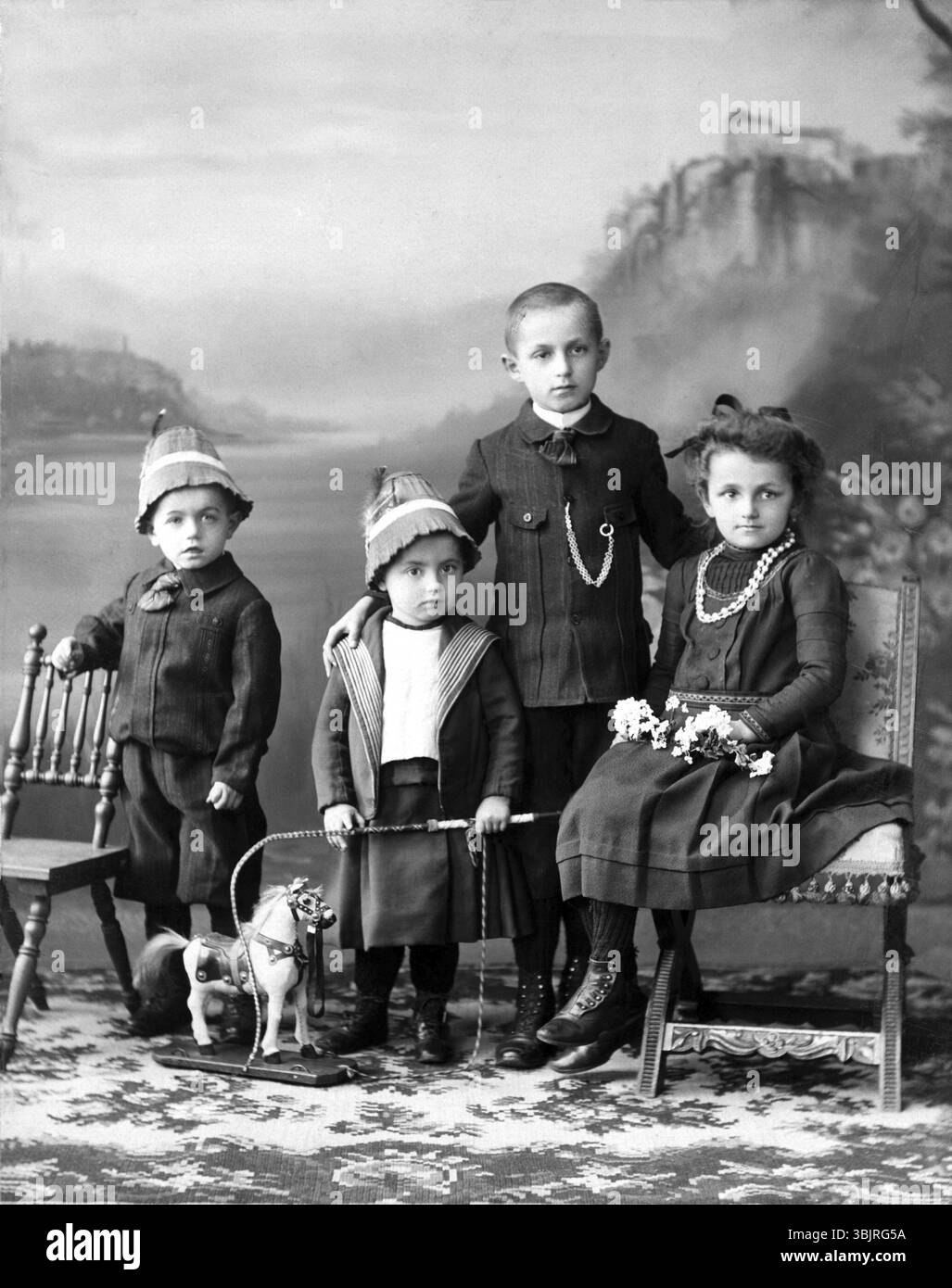 4 siblings, 1900, Four formally dressed children posing with toys and ...